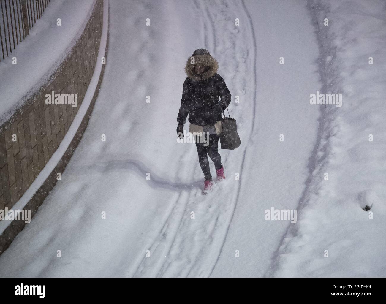 A woman walks through a heavy snowfall in central Stockholm, Sweden, on ...