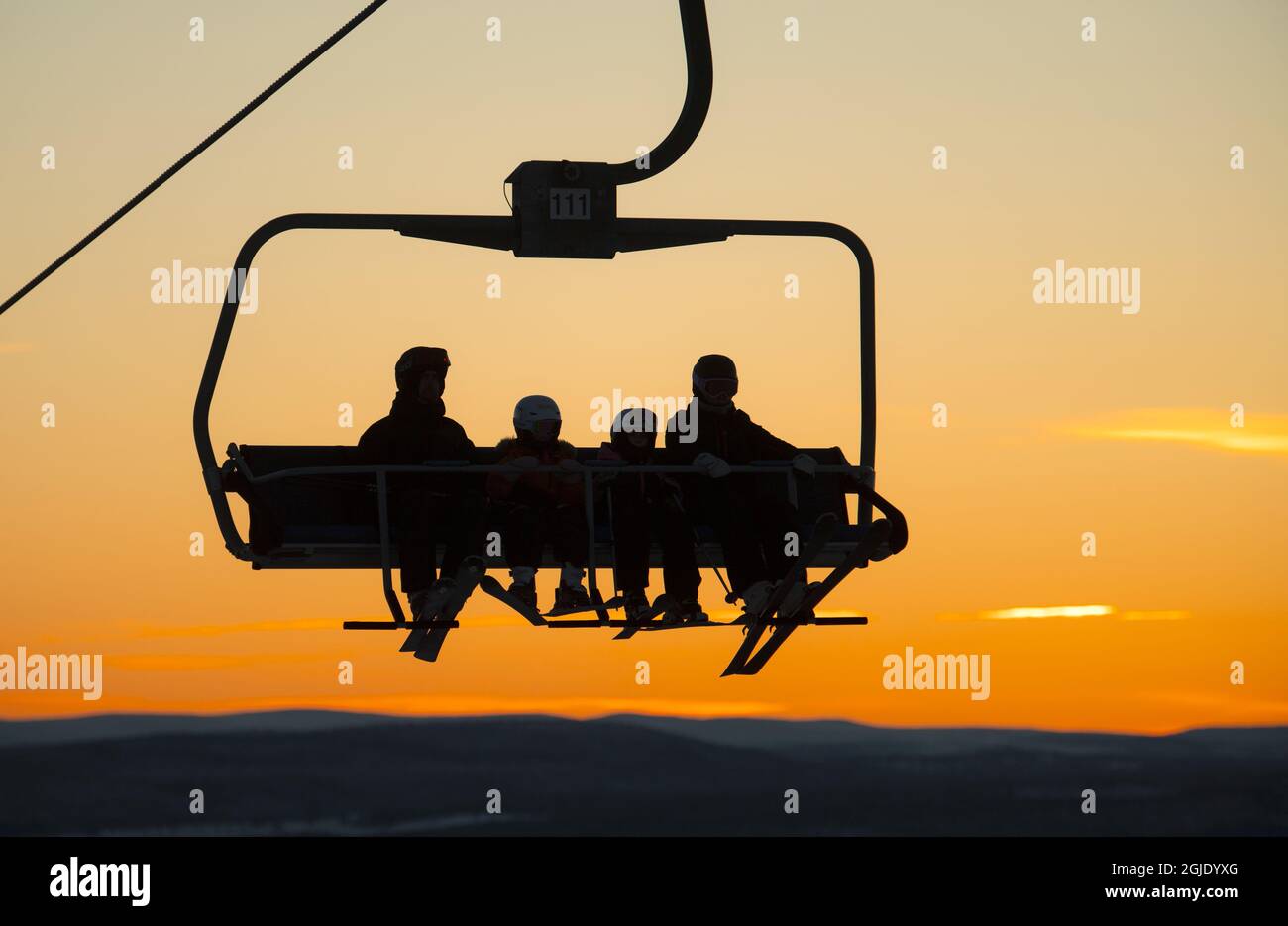 Four people, a family, in a ski lift as the sun sets in Idre, Sweden ...