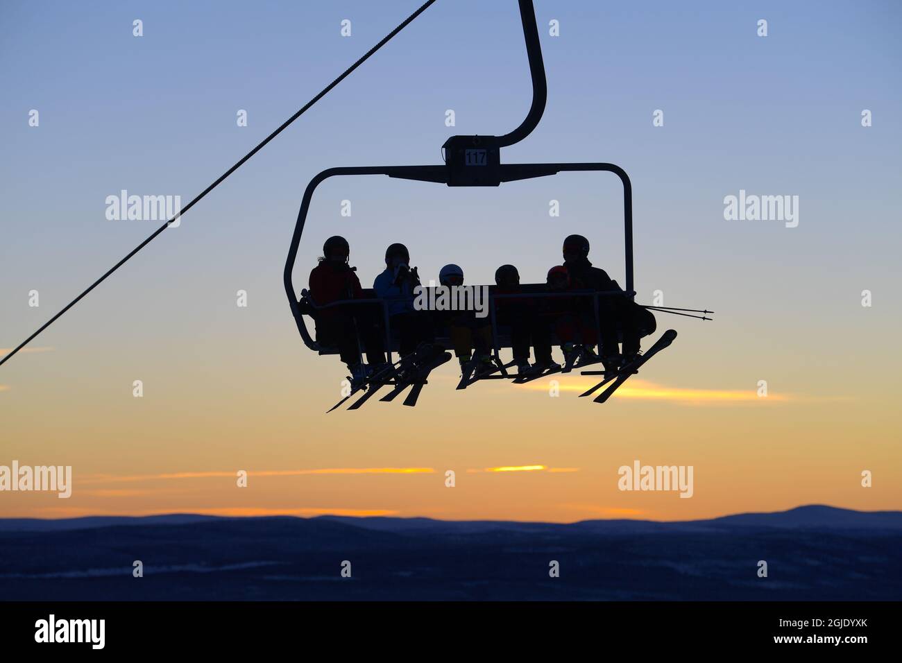 Four people, a family, in a ski lift as the sun sets in Idre, Sweden ...