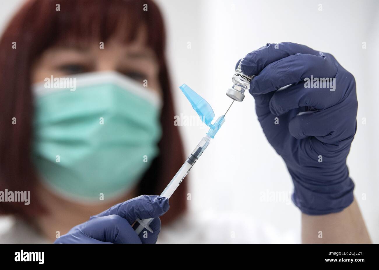 Nurse with gloved hands preparing a syringe with Comirnaty Covid-19 ...