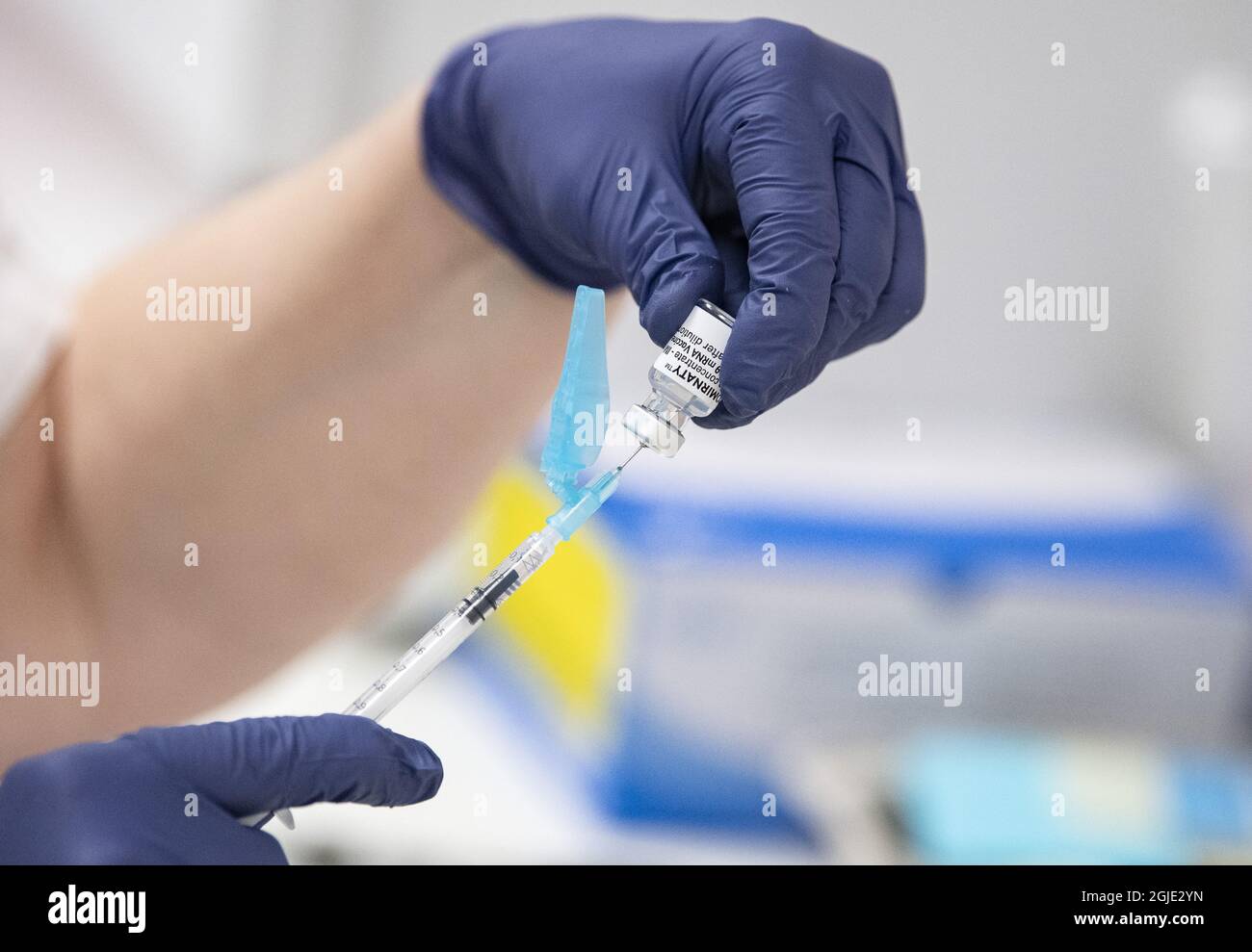 Gloved hands preparing a syringe with Comirnaty Covid-19 vaccine made ...