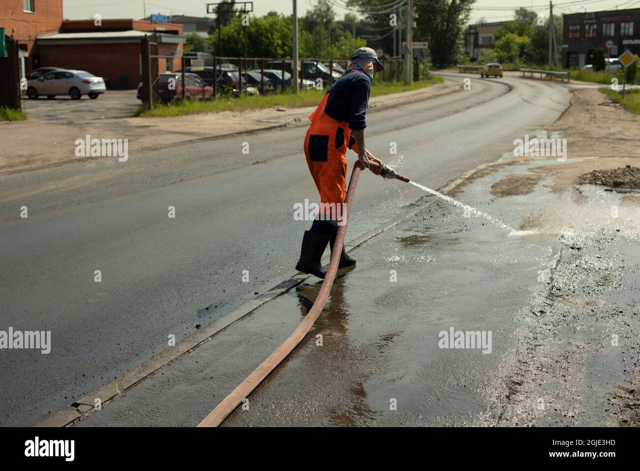 A worker washes the road with a hydrant. Hose with water jet. Washing ...