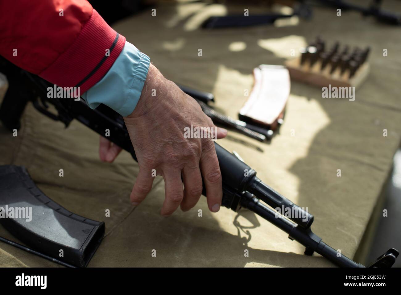 A man disassembles a firearm. A person undergoes military training ...