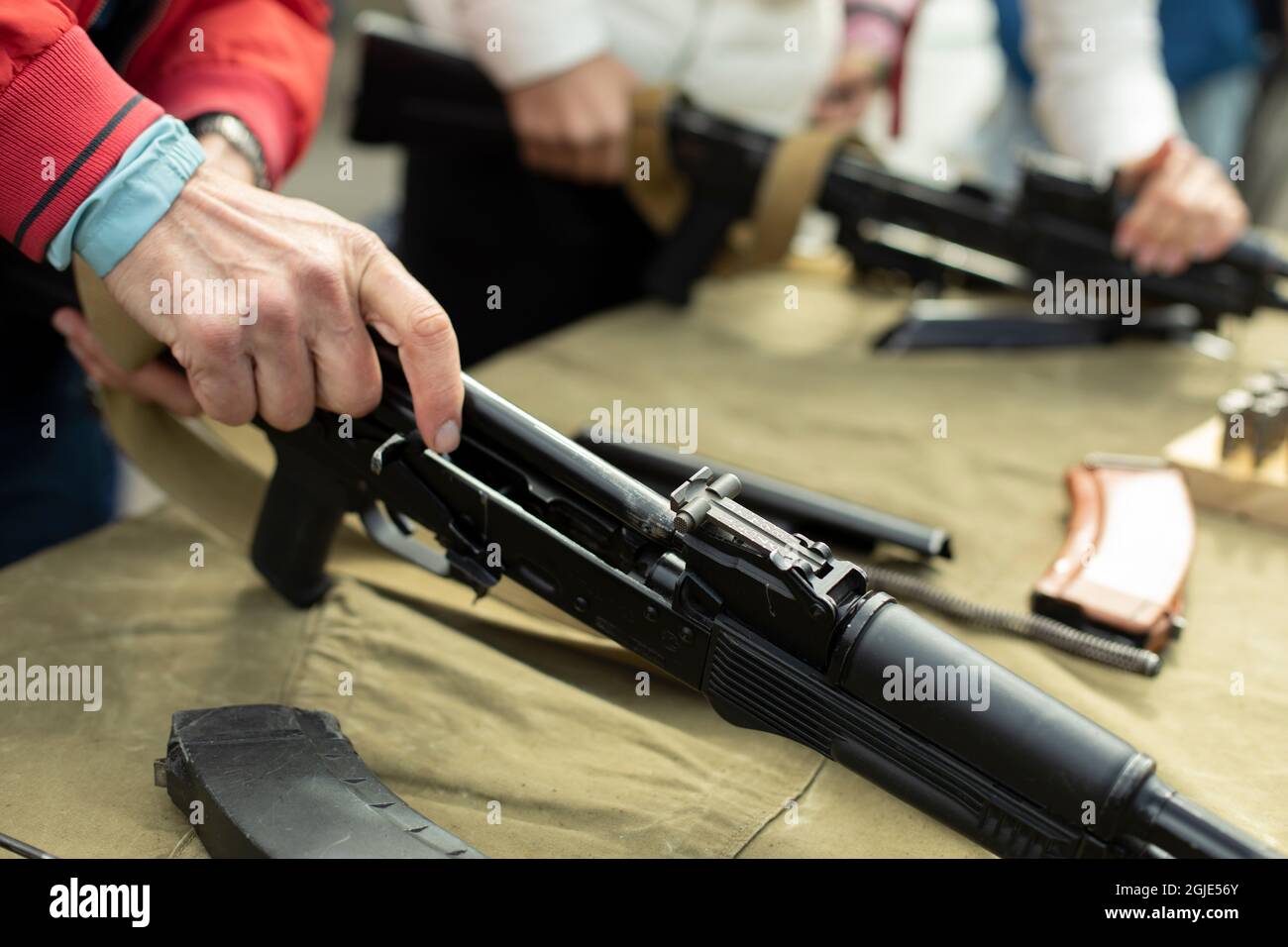 A man disassembles a firearm. A person undergoes military training ...