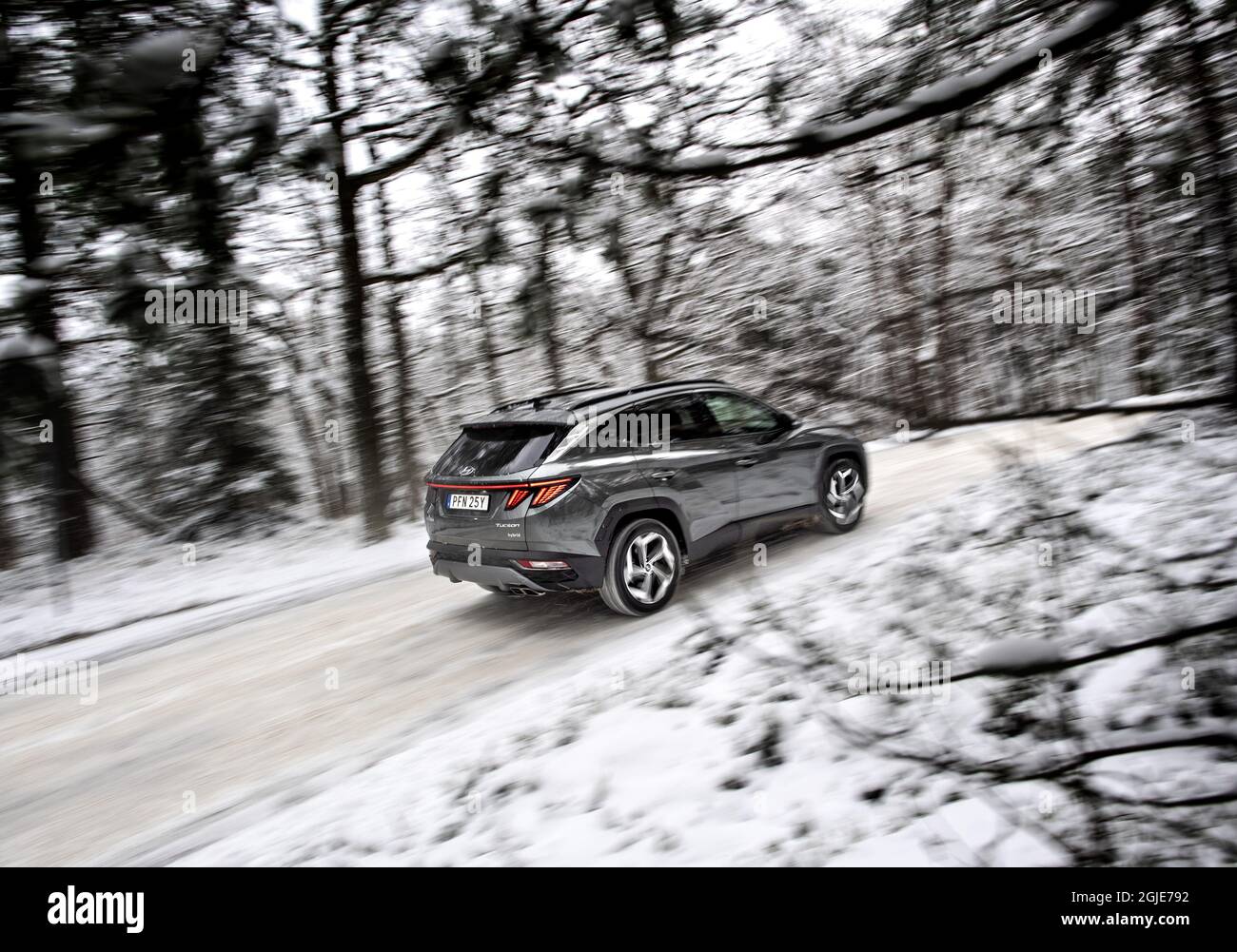 Hyundai Tucson 1,6 TGDI HEV 4WD Hybrid driving on a snowy road. Photo ...