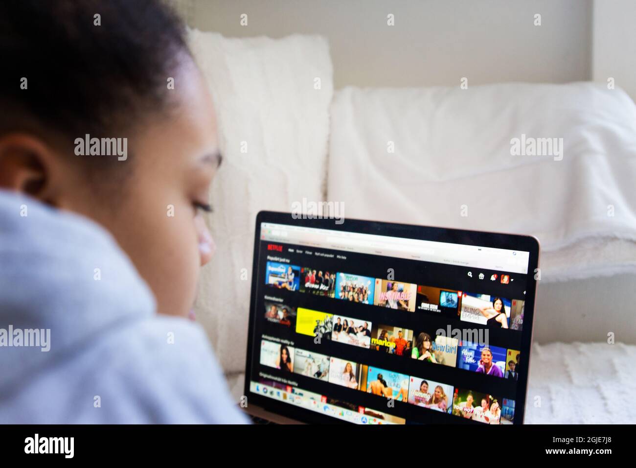 Teenage girl on her bed using a laptop computer watching, streaming ...