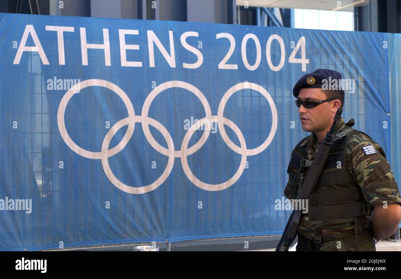 An armed security guard stands in front of the Olympic Rings at the ...