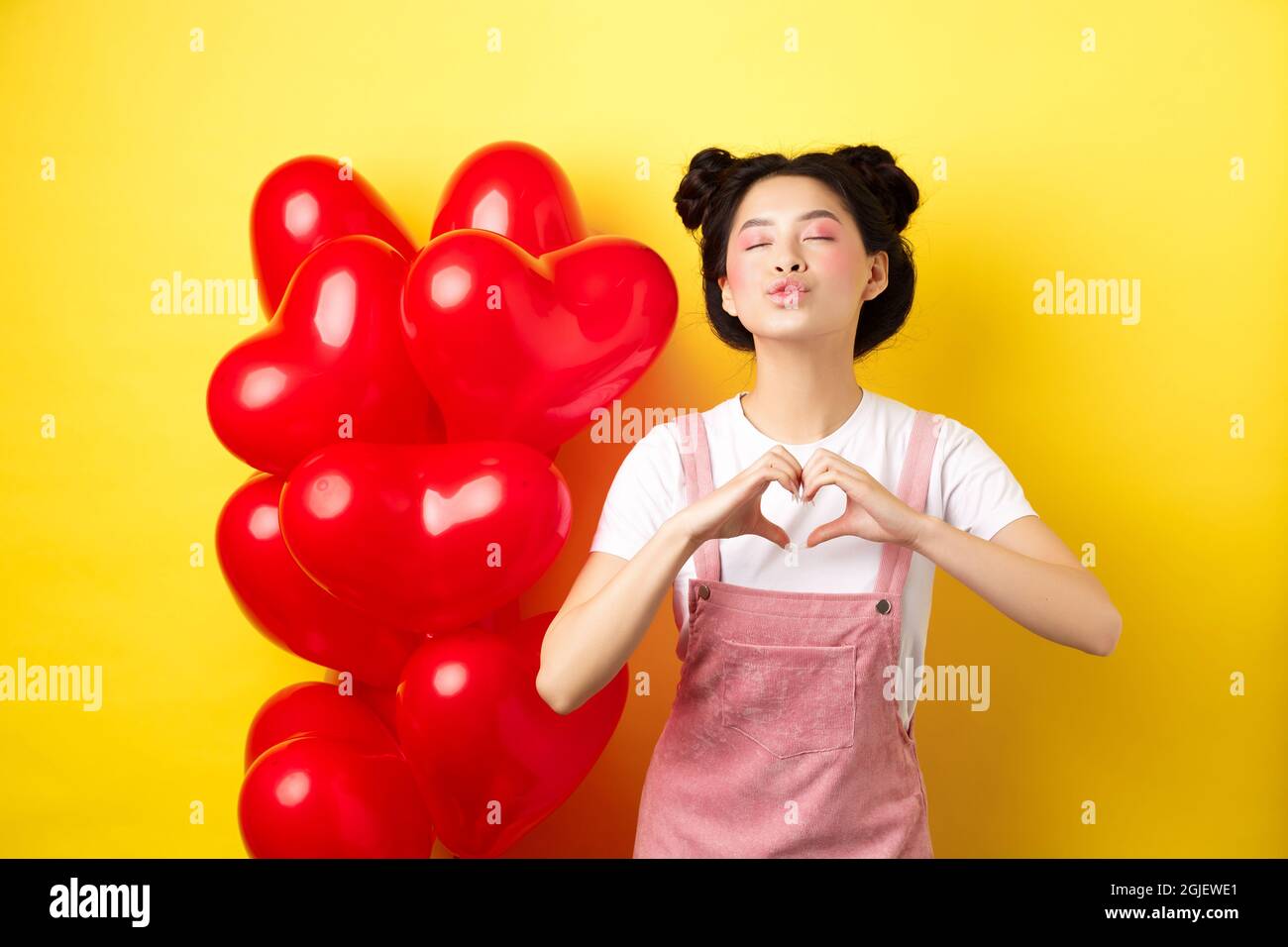 Romantic girl close eyes and pucker lips for kiss, showing I love you ...