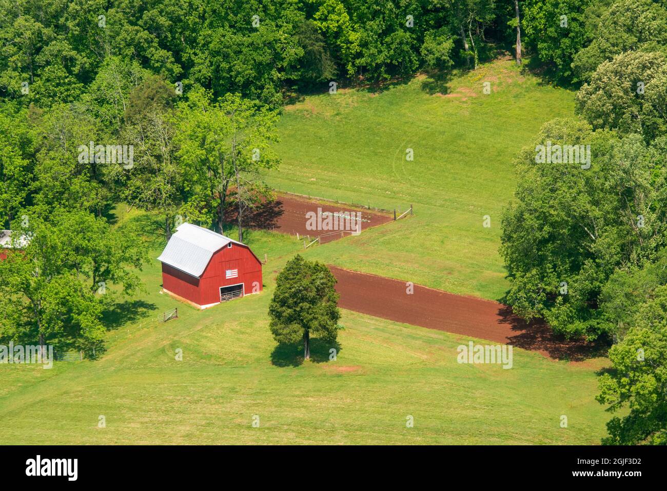 USA, Tennessee. Aerial of red barn contrast to green field and garden ...