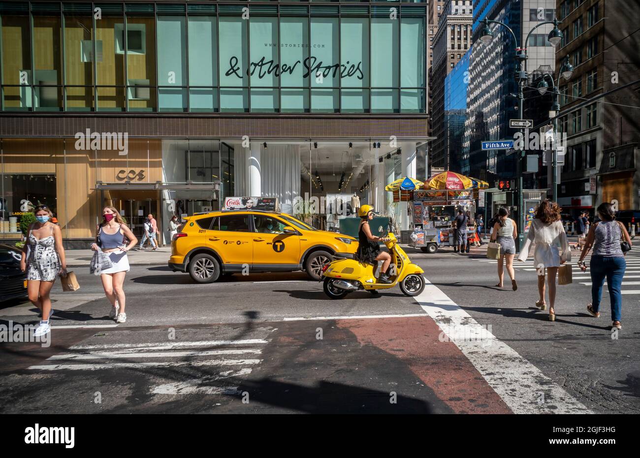 Big yellow taxi and small yellow scooter in Midtown Manhattan in New ...