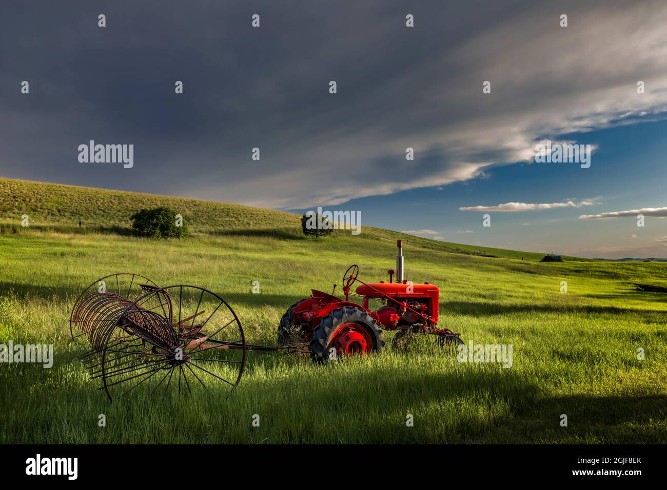 Old red tractor and hay rake abandoned in farm field, Palouse region of ...