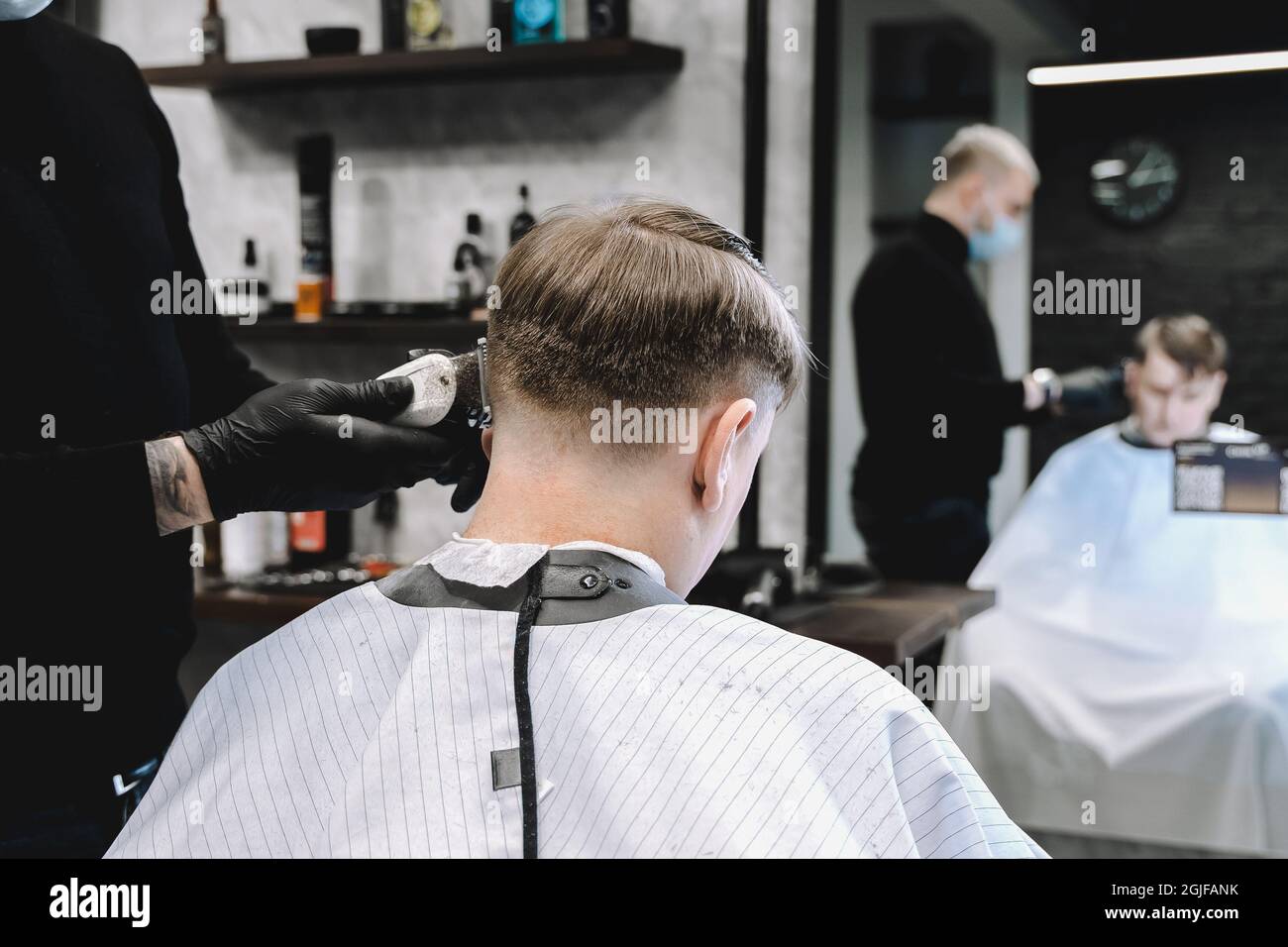Visit to the barbershop. Hairdresser, barber shaves client's temples ...