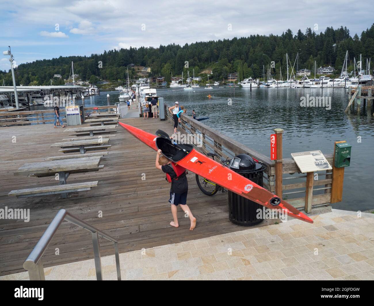 Usa, Washington State, Gig Harbor, boy carrying kayak on dock Stock ...
