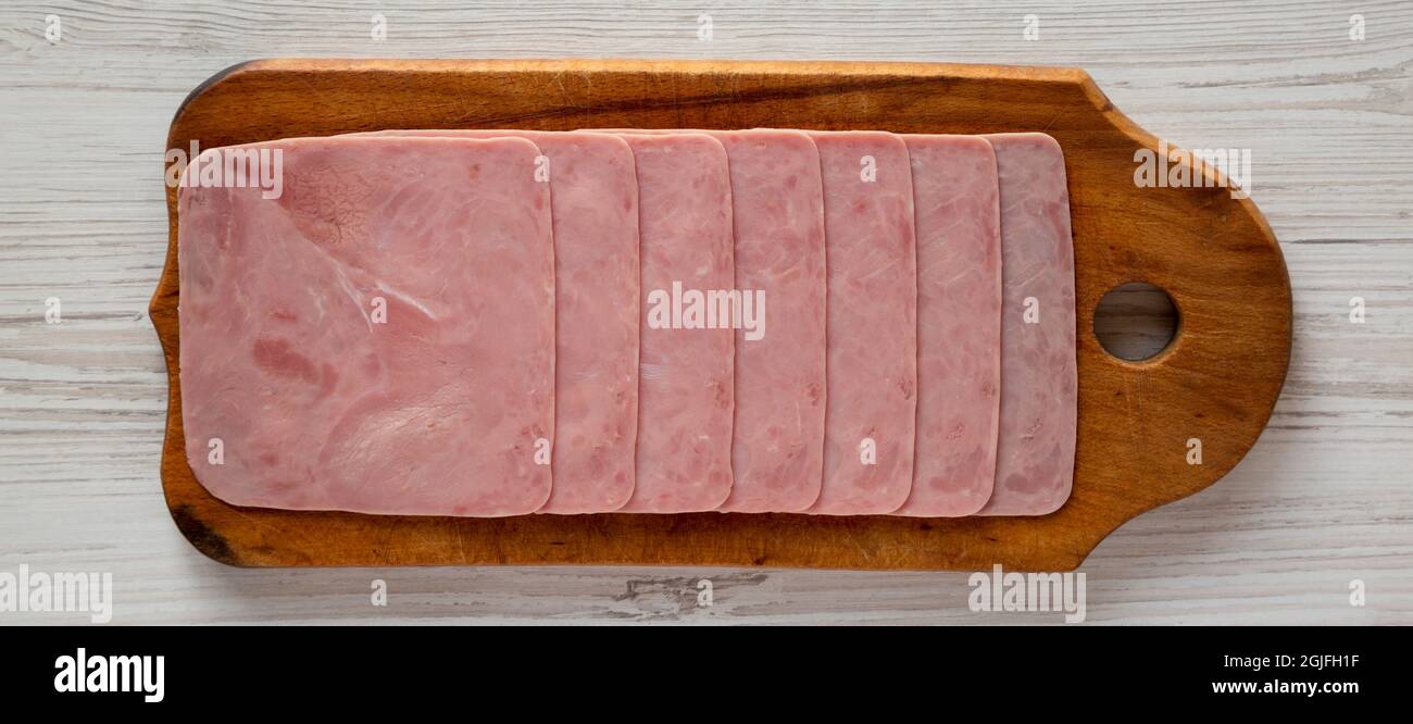 Organic Jamon Cocido Extra on a rustic wooden board on a white wooden ...