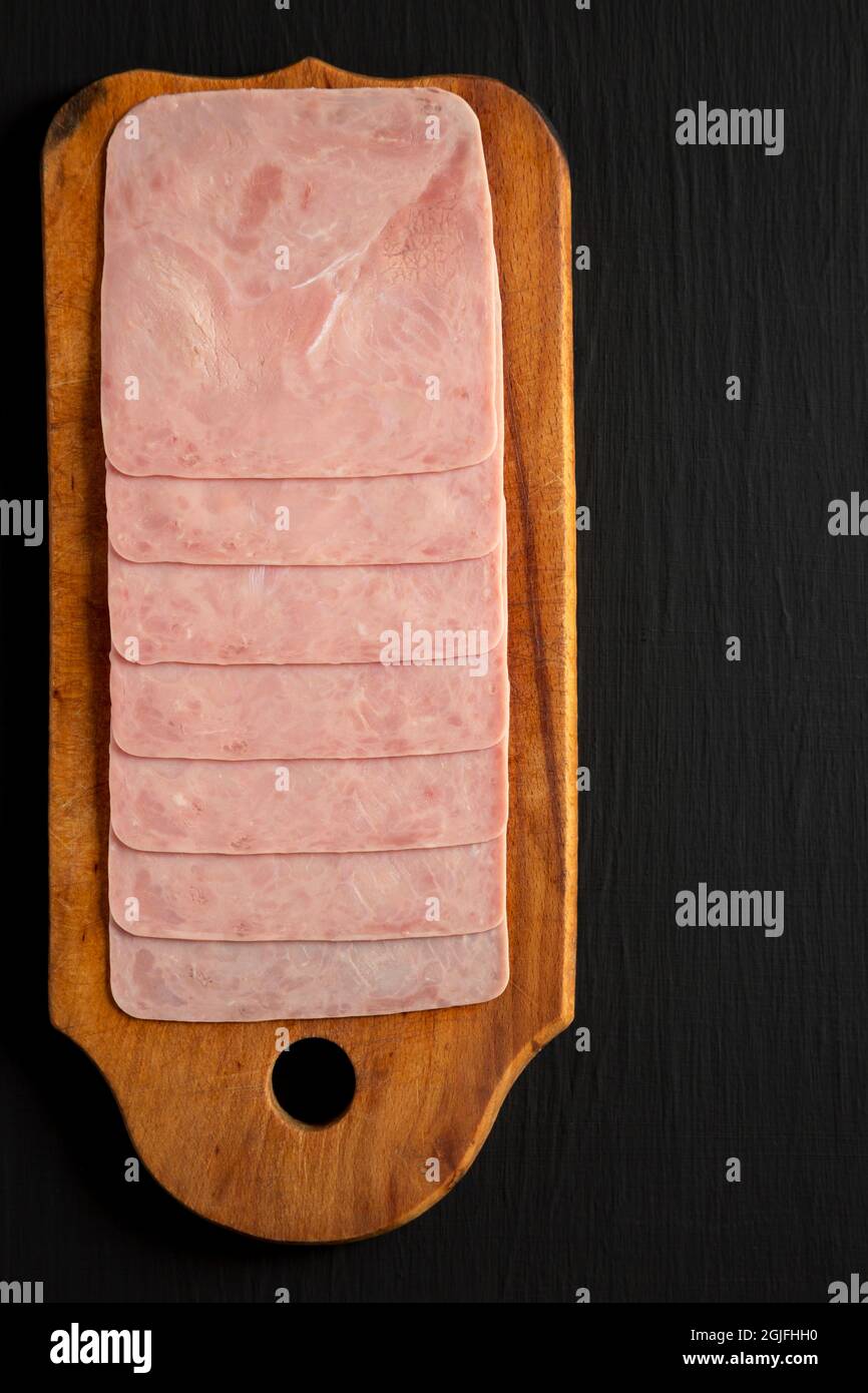 Organic Jamon Cocido Extra on a rustic wooden board on a black ...
