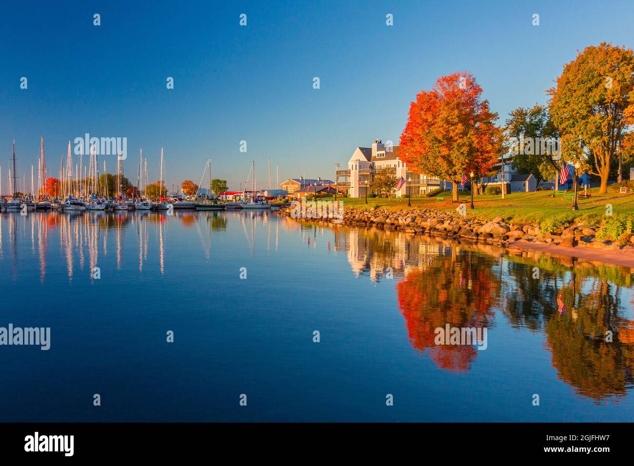 USA, Wisconsin. Fall colors reflected on the still waters of the harbor ...