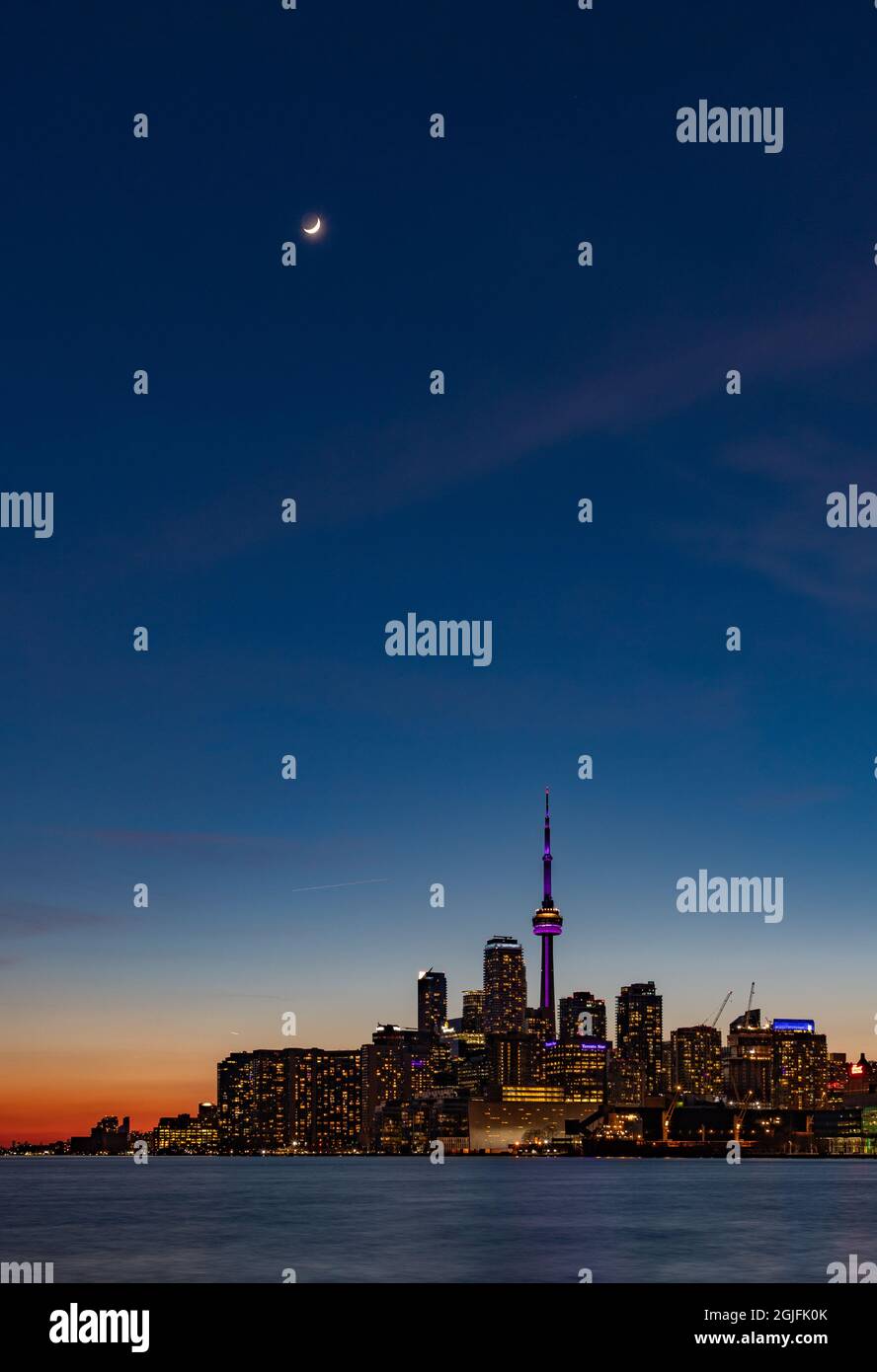 A picture of Toronto at night with the moon visible high in the sky ...