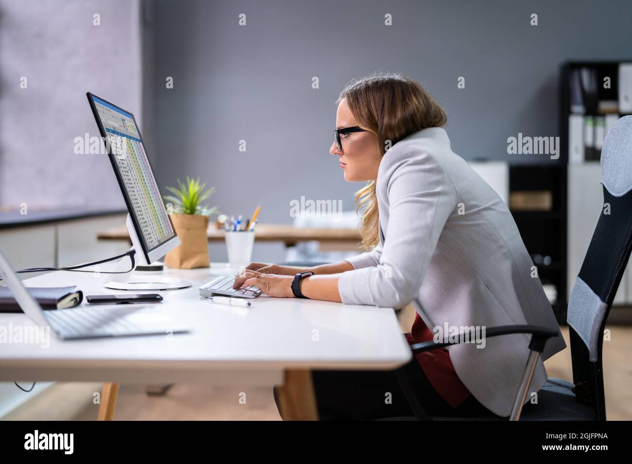 Woman Sitting In Bad Posture Working On Computer In Office Stock Photo ...