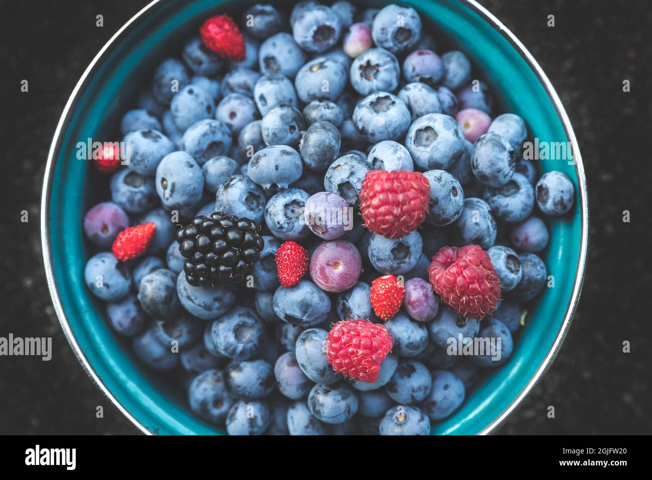 Top view of blueberries, raspberries and blackberries inside of a blue ...
