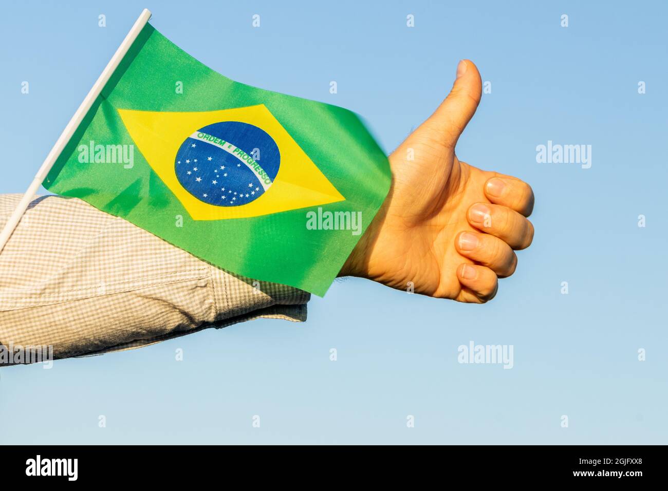A man holding a flag of brazil in his hand and holding his thumb up in ...