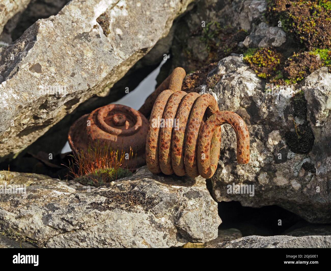 rusty coil Spring & metalwork abandoned on dry stone wall with moss ...