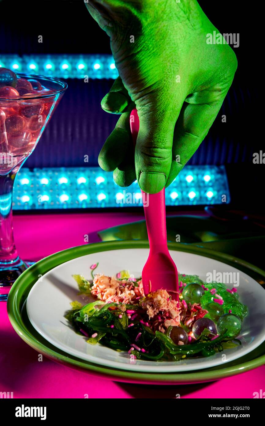 Science fiction green alien from outer space eating dinner at a fancy ...