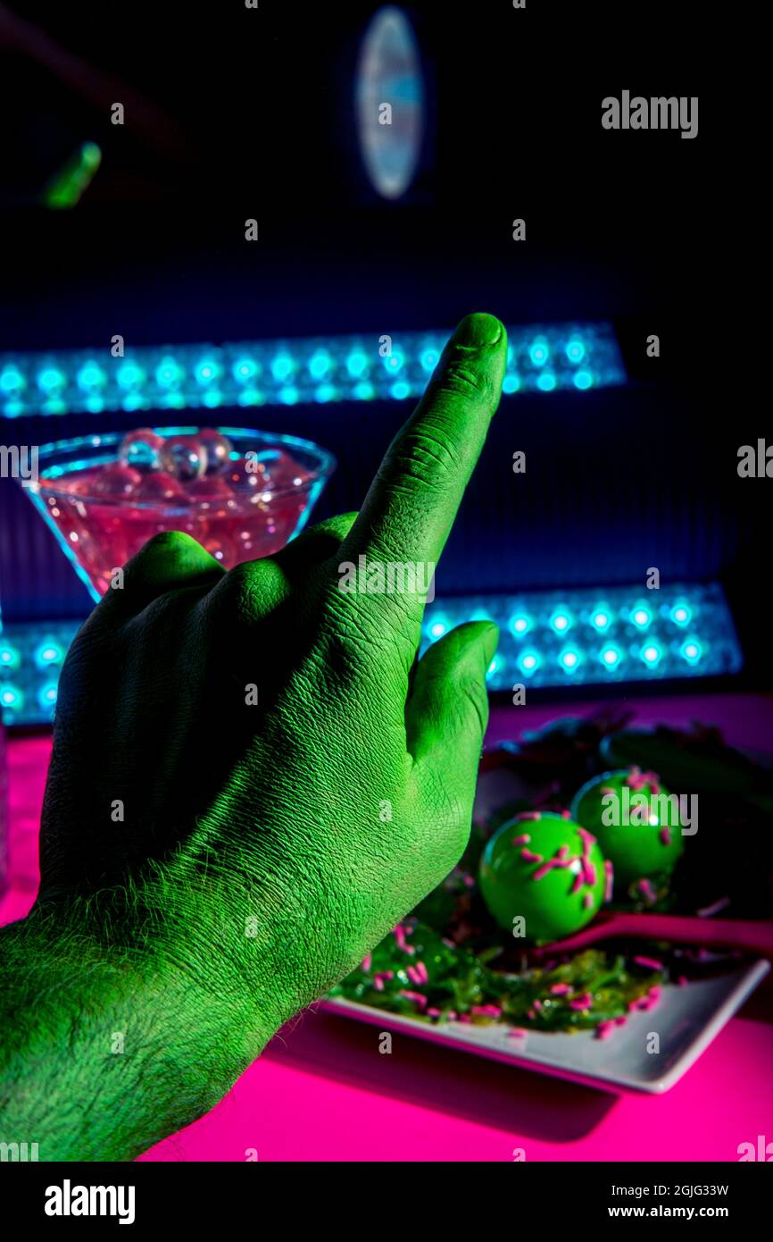 Science fiction green alien from outer space eating dinner at a fancy ...