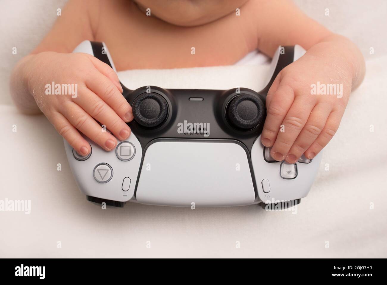 a newborn baby is holding a playstation. fingers of the hands of a ...