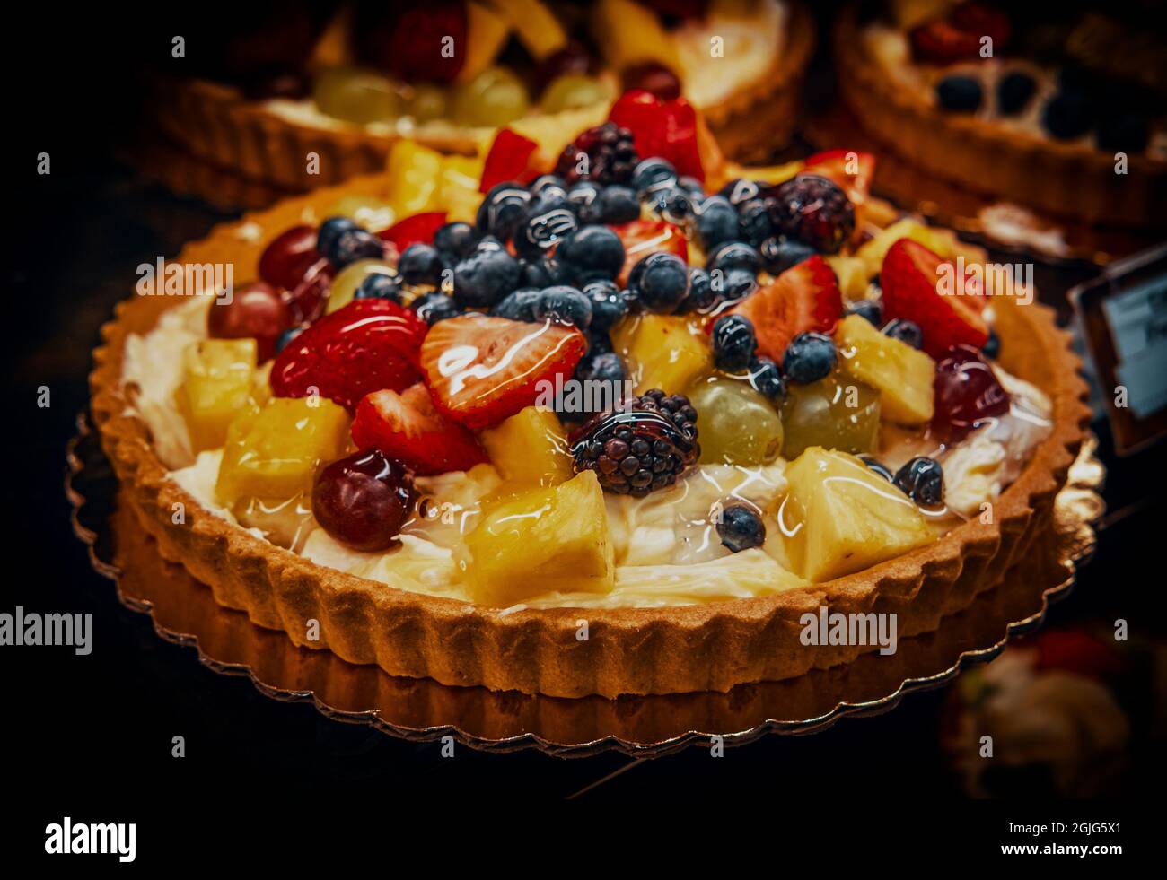 Fresh fruit tart on display at local bakery dessert shop Stock Photo ...