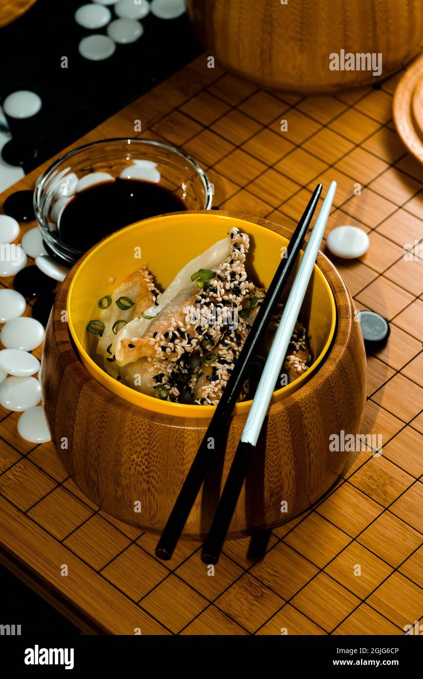 Playing Go board game while eating Chinese dumplings with tuxedo sesame ...