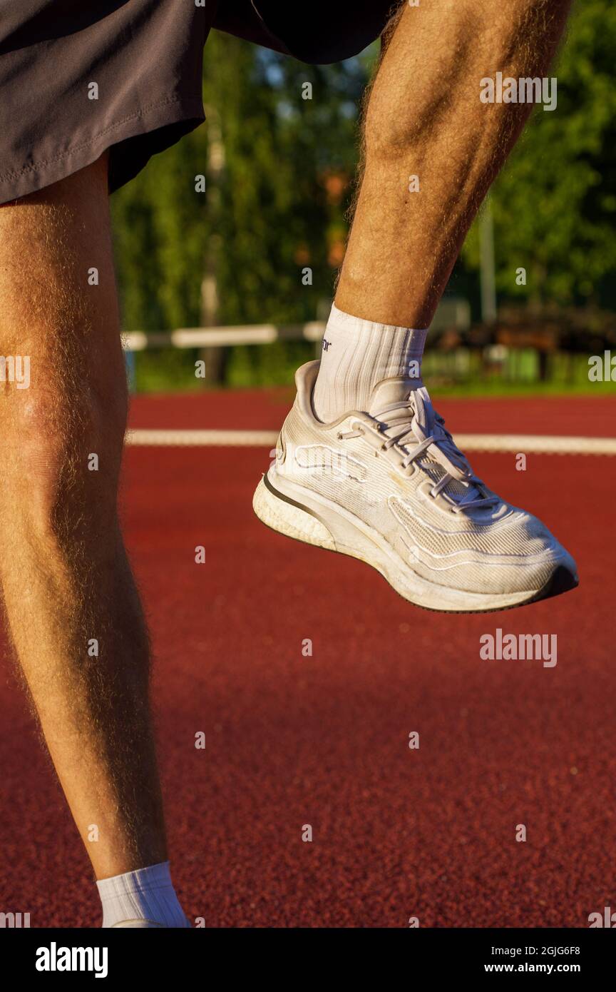 Close up young man runner athlete getting ready to run doing warm up ...