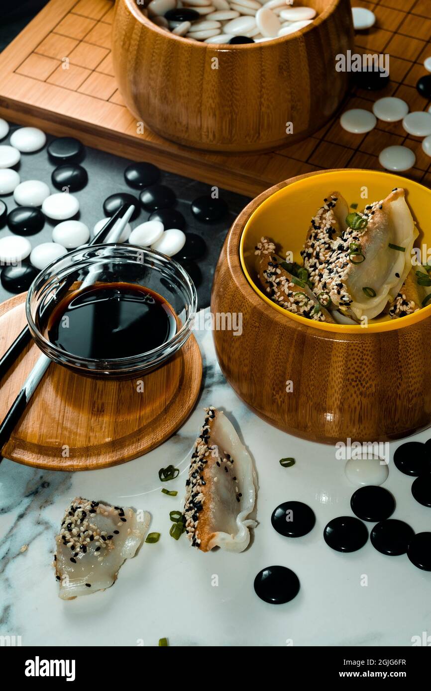 Playing Go board game while eating Chinese dumplings with tuxedo sesame ...
