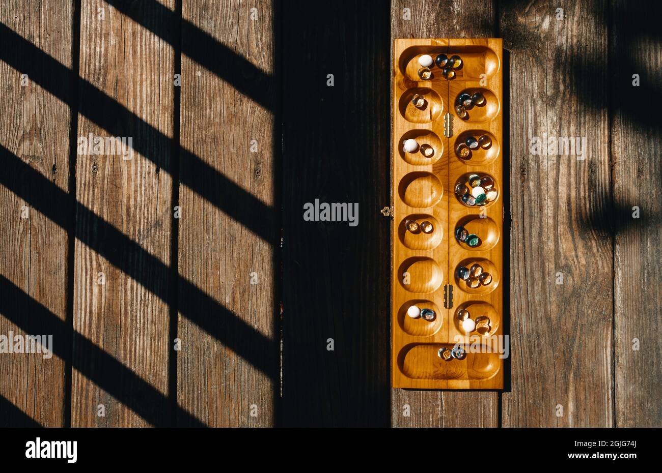 Traditional Mancala boardgame with glass pieces with hard light shadow ...