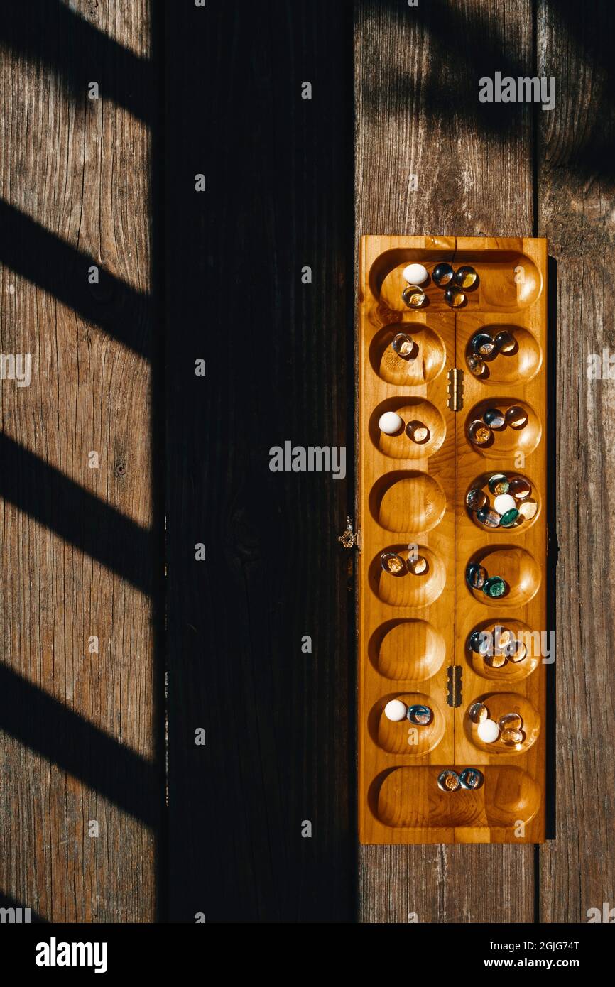 Traditional Mancala boardgame with glass pieces with hard light shadow ...