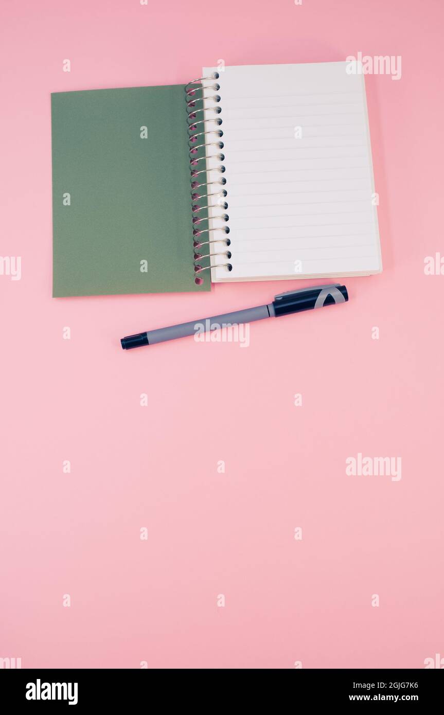 Vertical shot of an open notebook with a penon a pink surface Stock ...