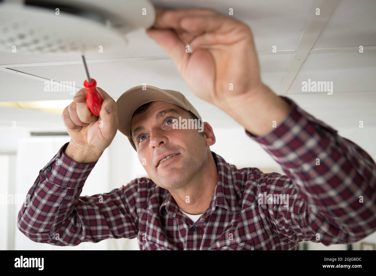 man fitting smoke detector to ceiling Stock Photo - Alamy