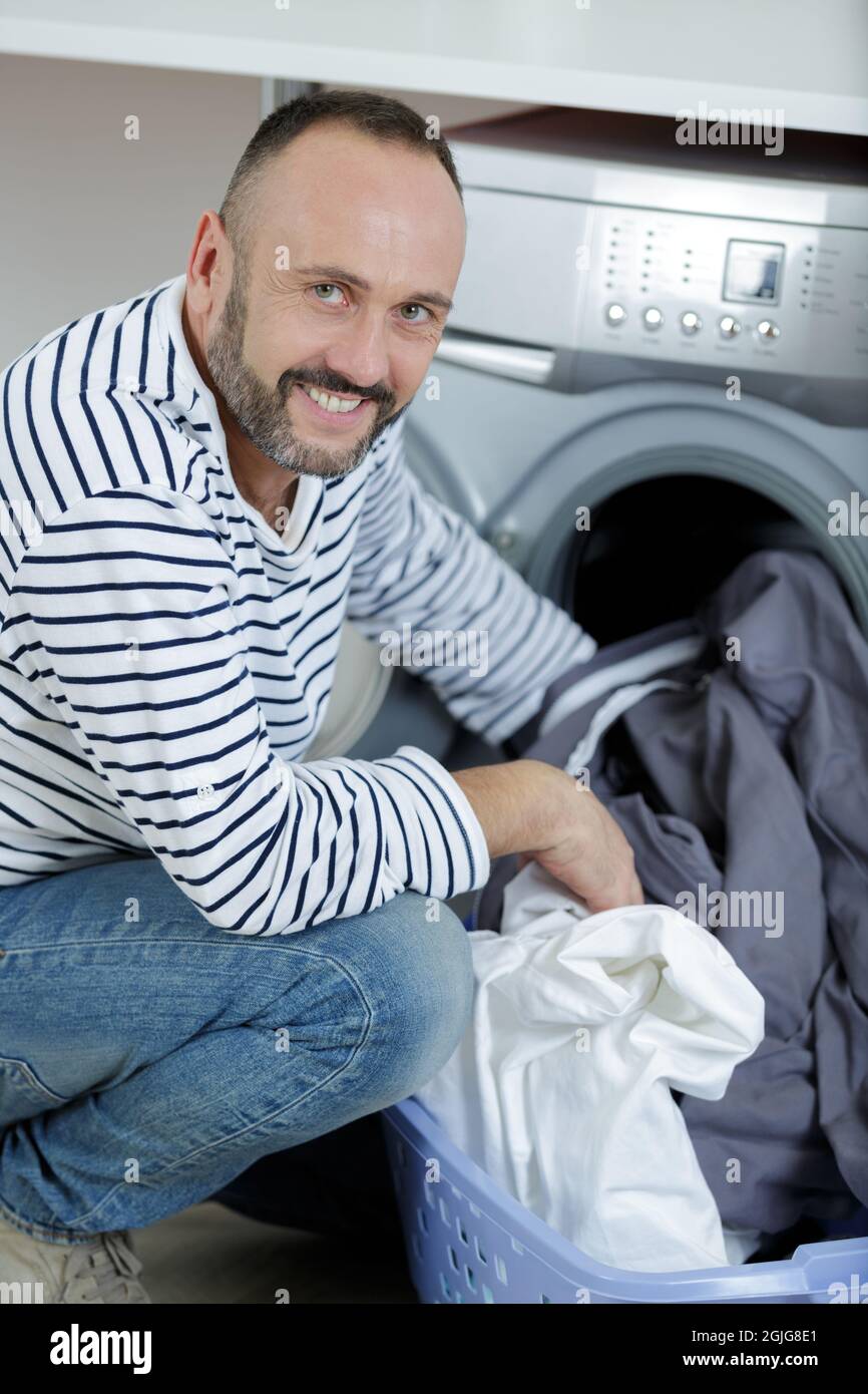 man loading clothes in washing machine Stock Photo - Alamy