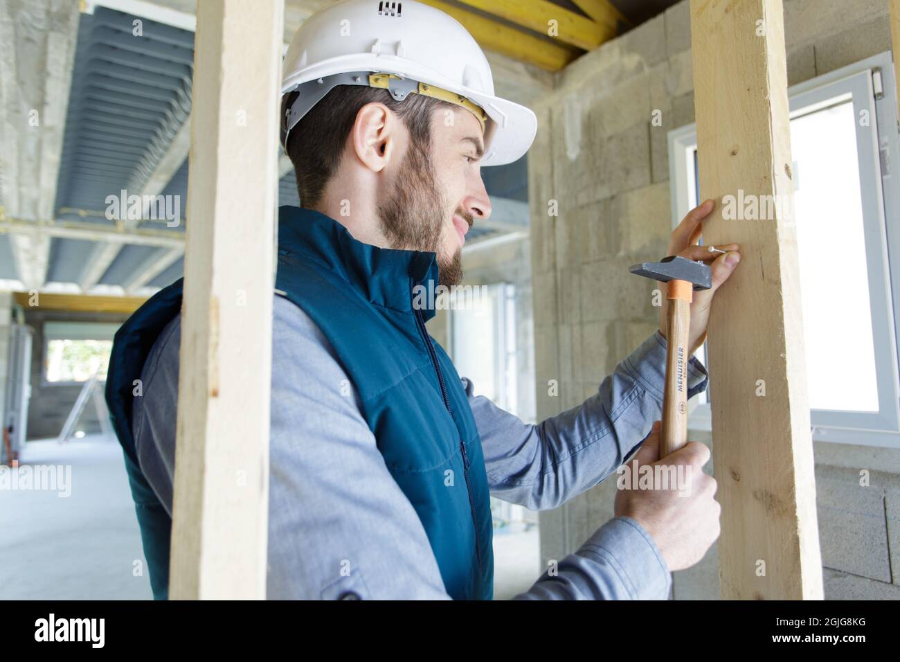 happy man builder hammer wood structure indoors Stock Photo - Alamy