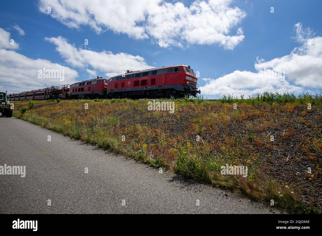 Train on the rail tracks in a field under the sunlight and a blue ...