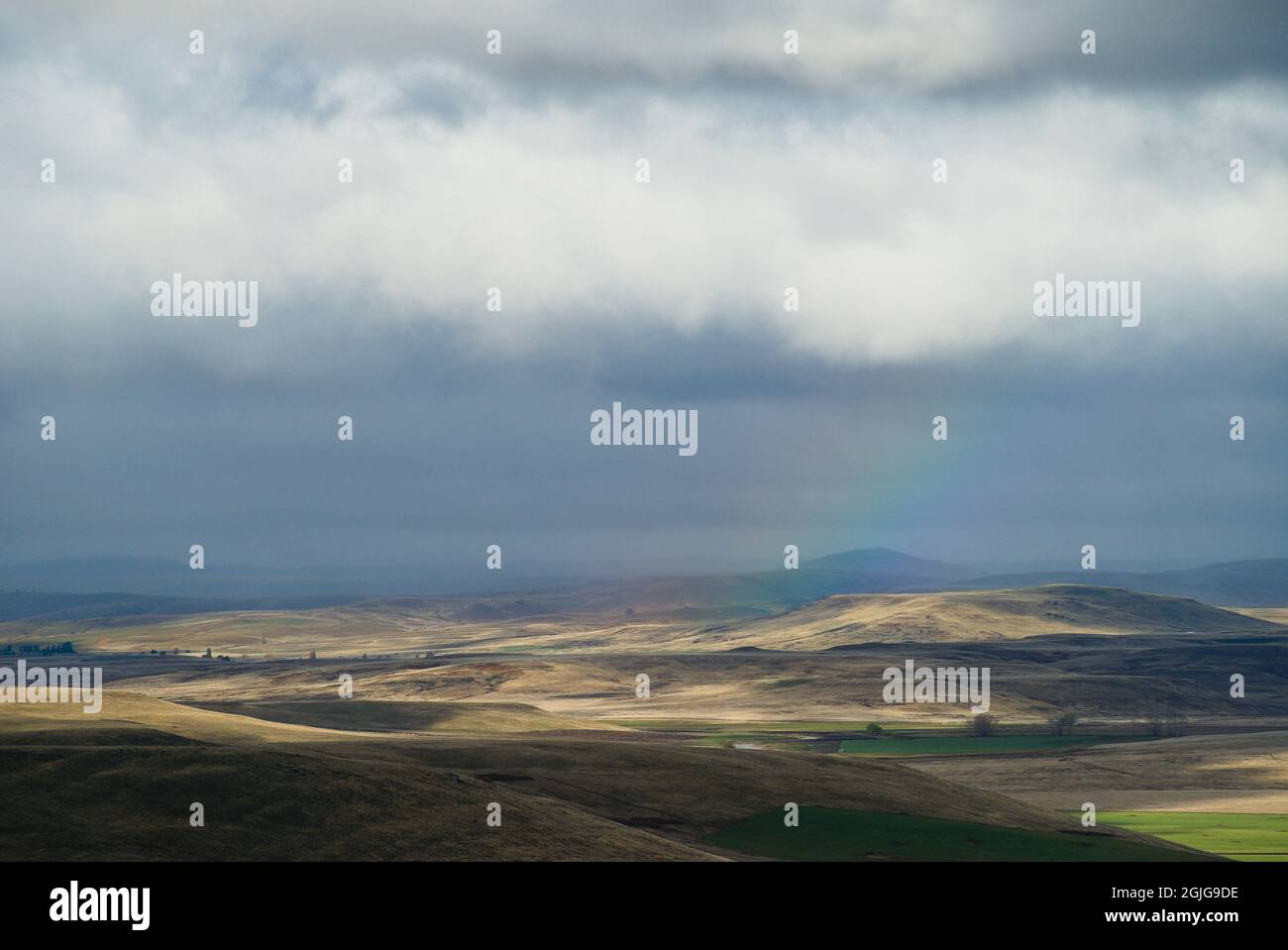View east across Monaro tablelands in rain and faint rainbow. Viewed ...