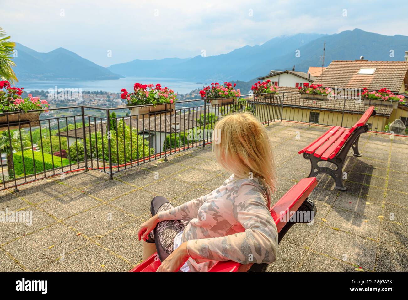 Woman sitting on top of Lake Maggiore in Switzerland. Swiss bench at ...