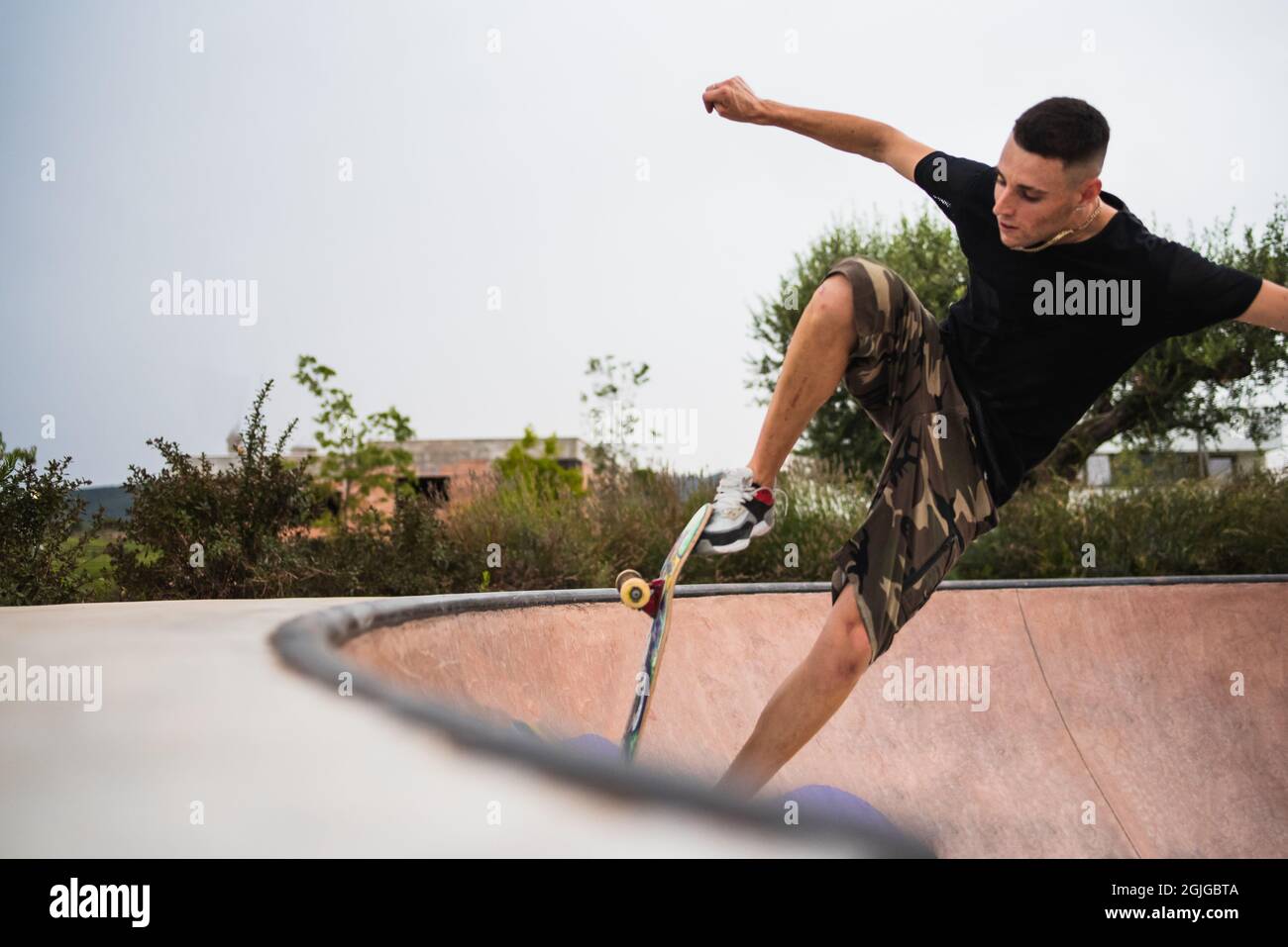 Skateboarder on shorts performing a trick in a pool at a skate park ...