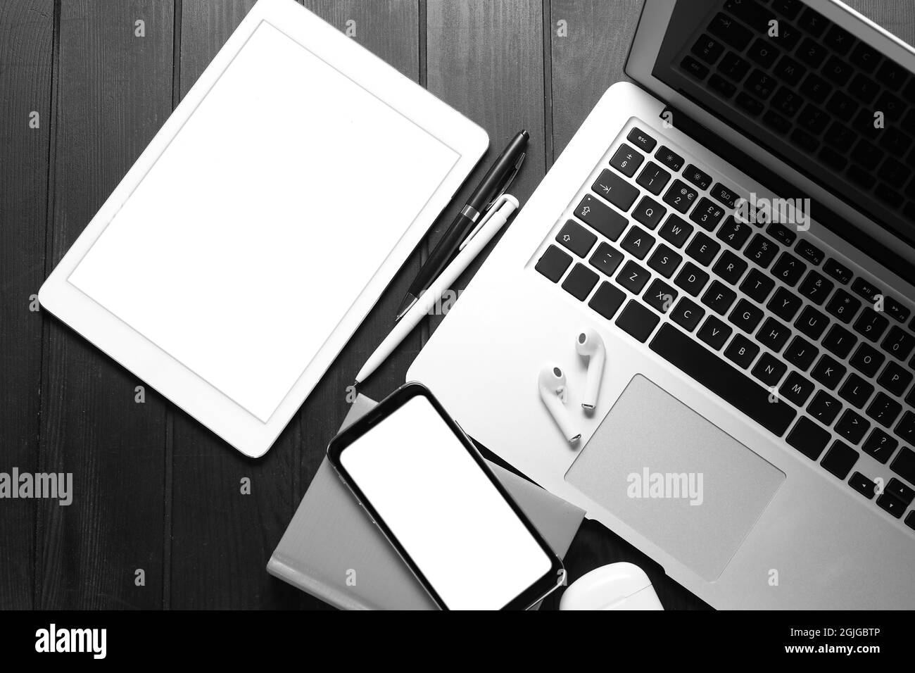 Different modern devices and notebook on dark wooden background Stock ...