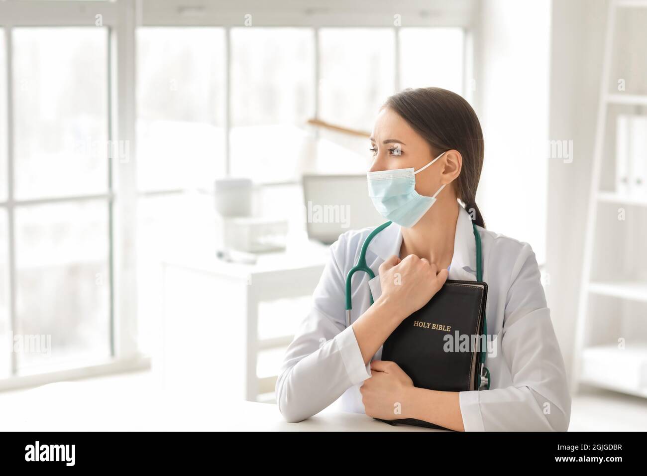 Praying female doctor in clinic Stock Photo - Alamy
