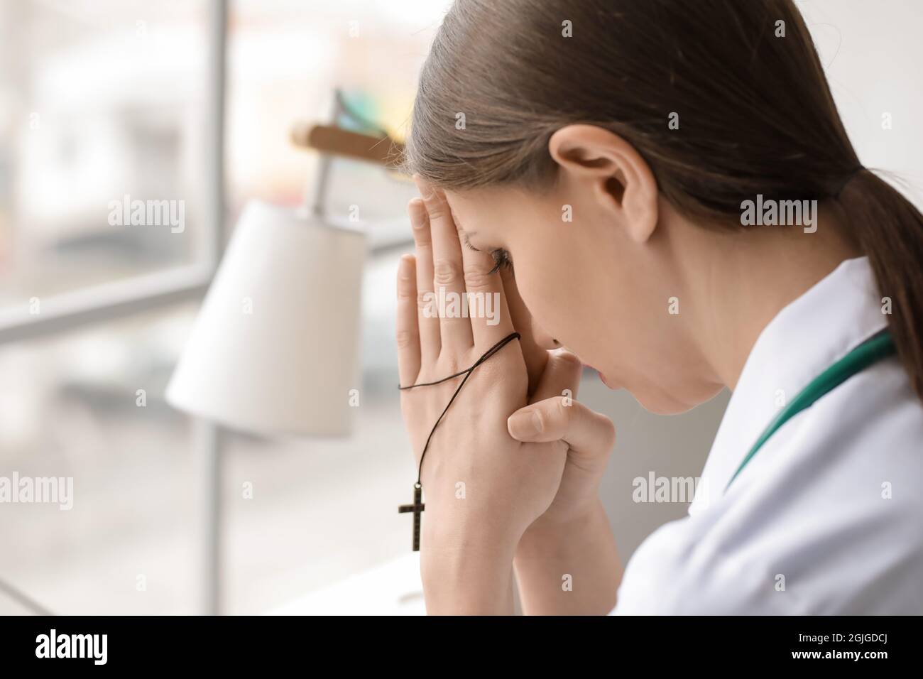 Praying female doctor in clinic Stock Photo - Alamy