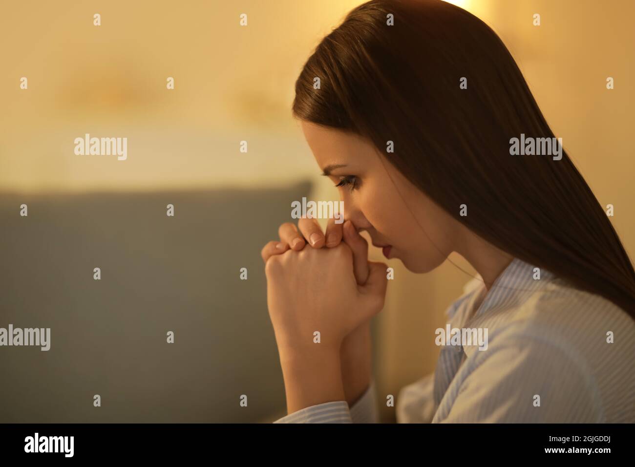 Praying young woman at home in evening Stock Photo - Alamy