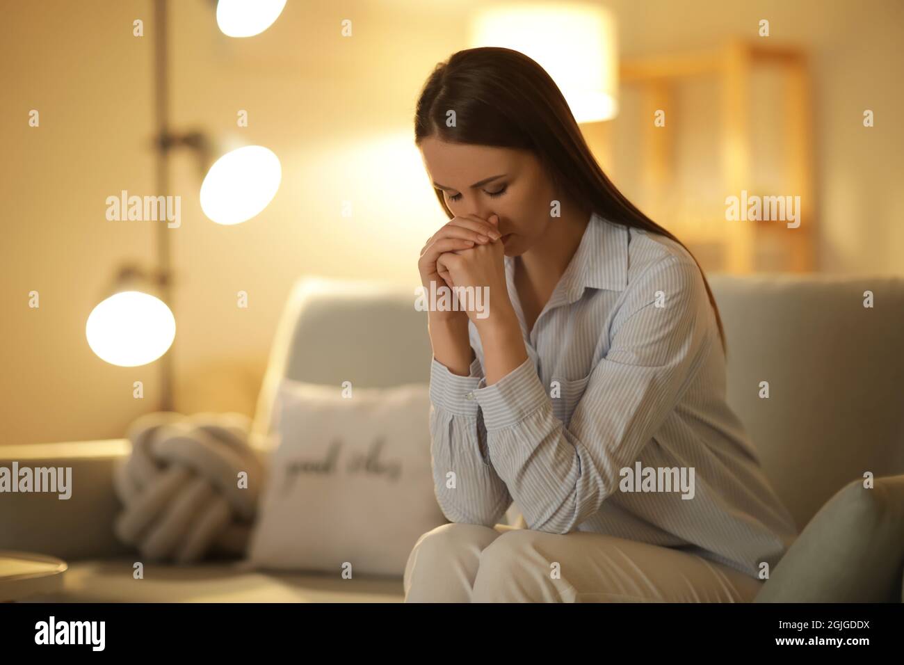 Praying young woman at home in evening Stock Photo - Alamy