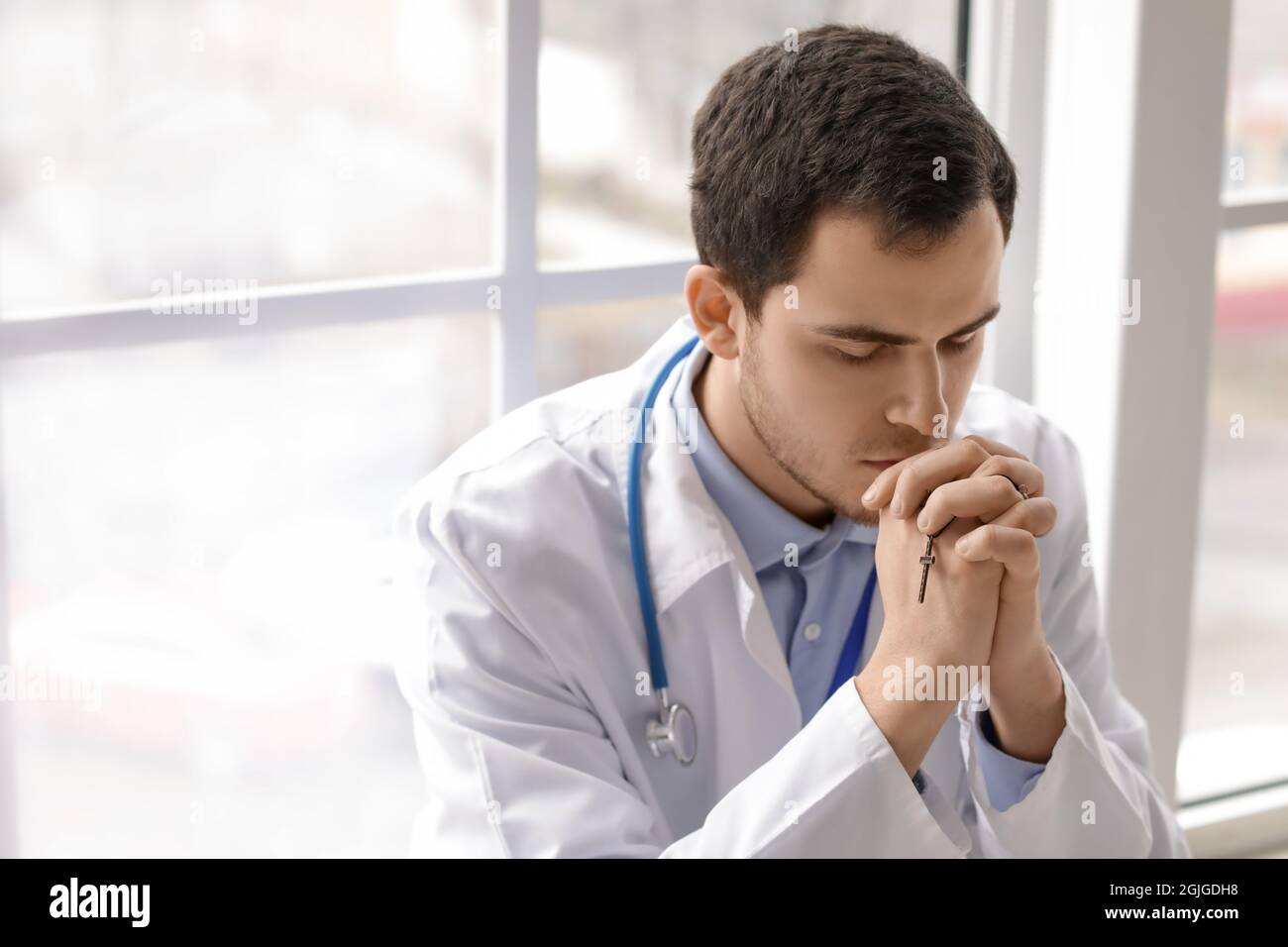 Religious doctor praying in clinic Stock Photo - Alamy