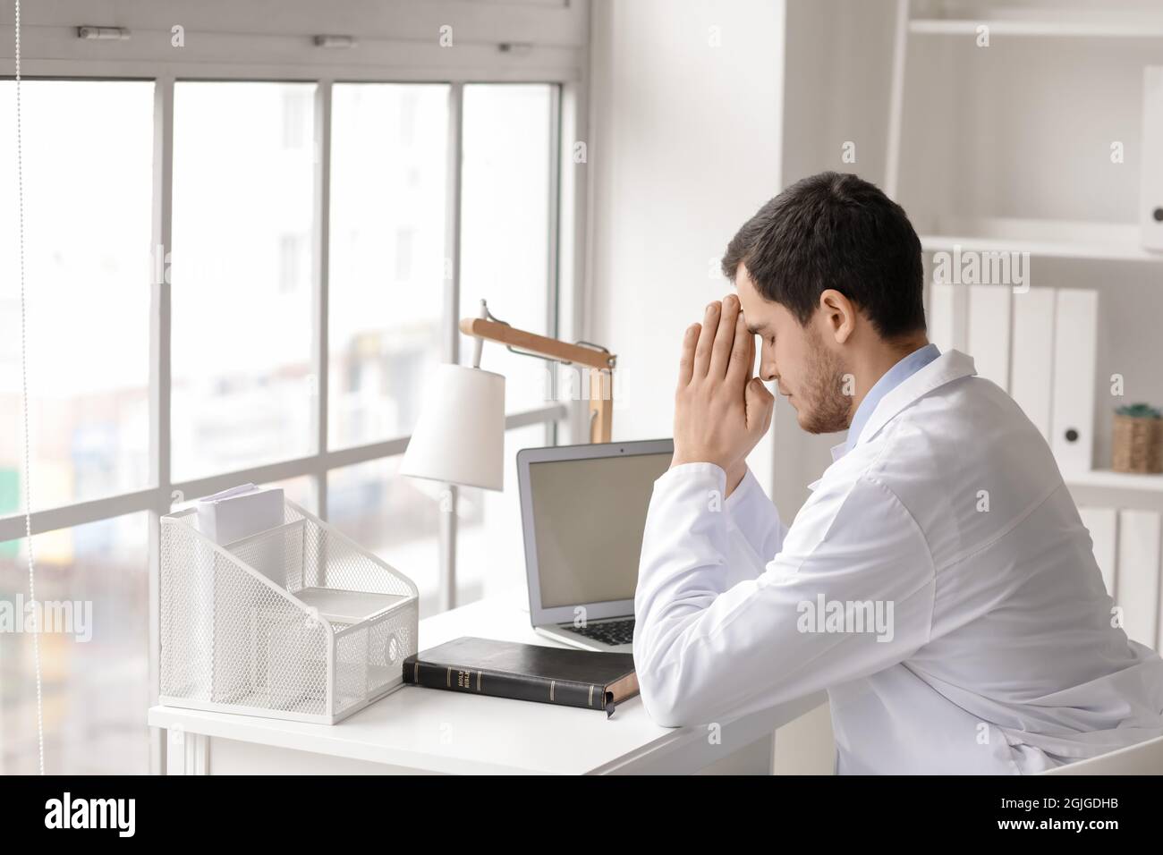 Religious doctor praying in clinic Stock Photo - Alamy