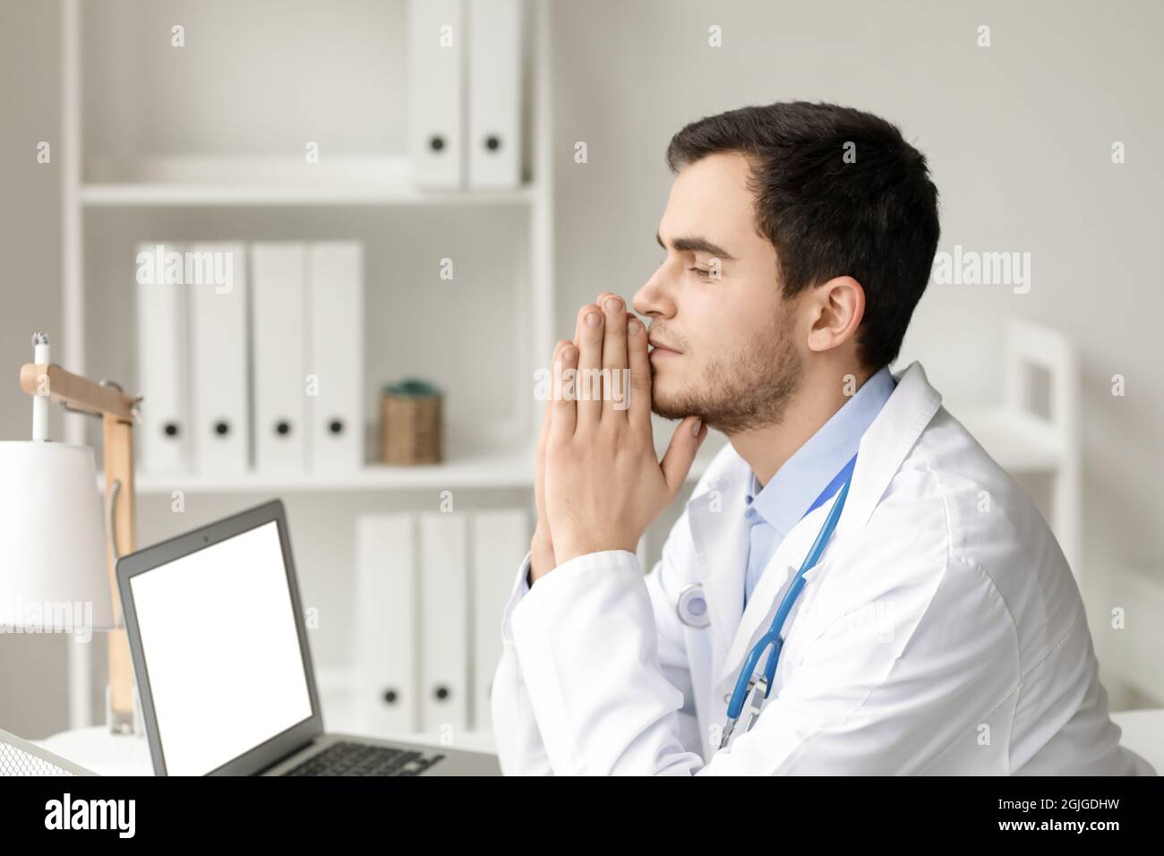 Religious doctor praying in clinic Stock Photo - Alamy